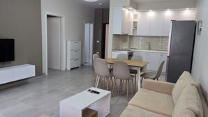 Uma sala de estar moderna com sofá, mesa de centro, televisão e um espaço de jantar com cadeiras e mesa.