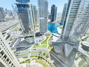 Zona urbana com edifícios altos e arquitetura moderna, uma rotatória central e um corpo de água.