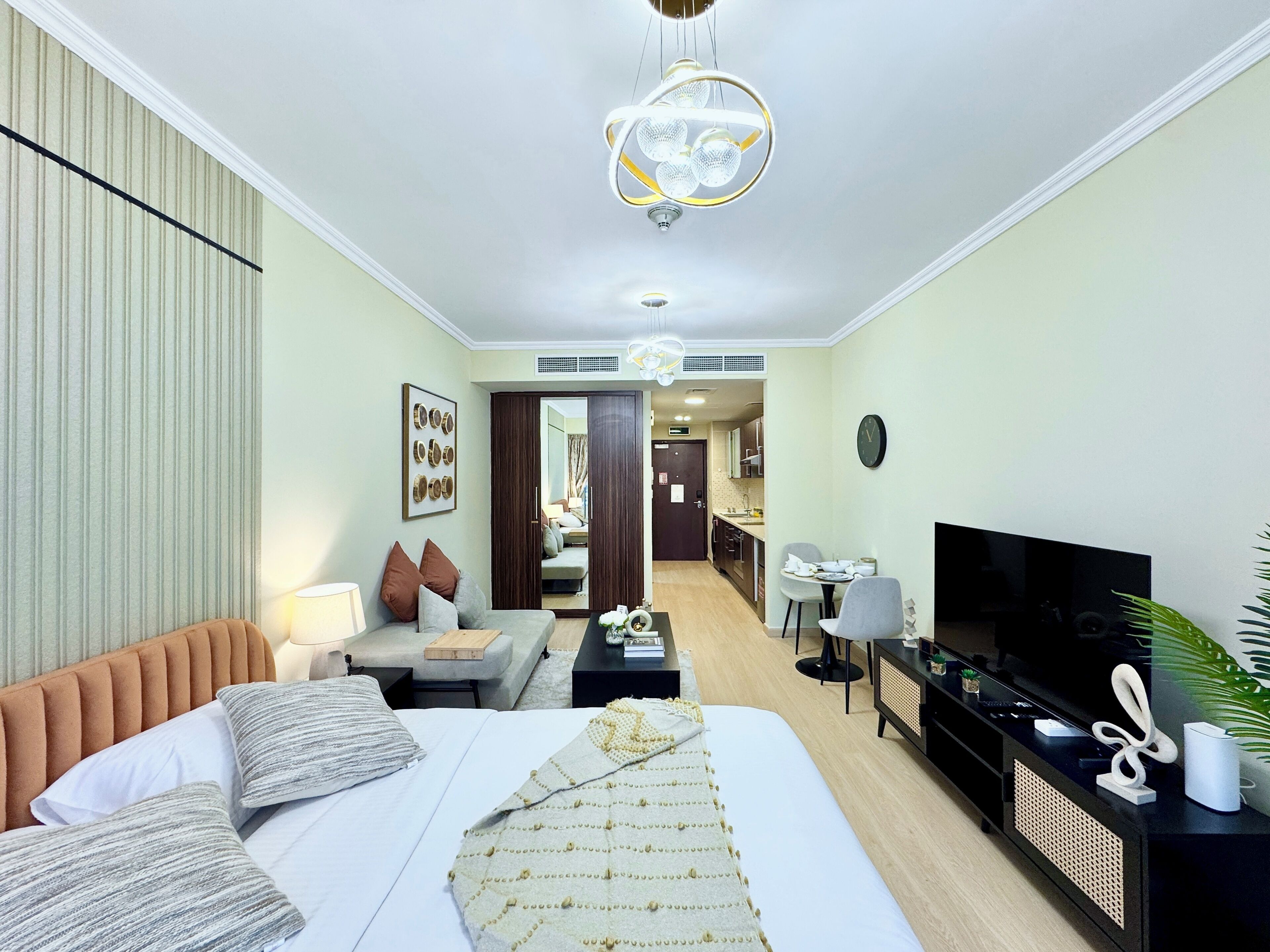 Quarto de hotel com cama, sofá, televisão e área de refeições.