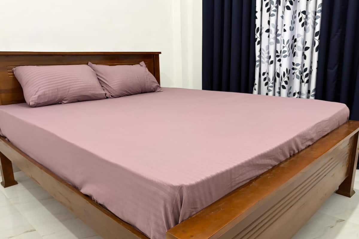Uma cama de solteiro com estrutura de madeira e colchão claro.