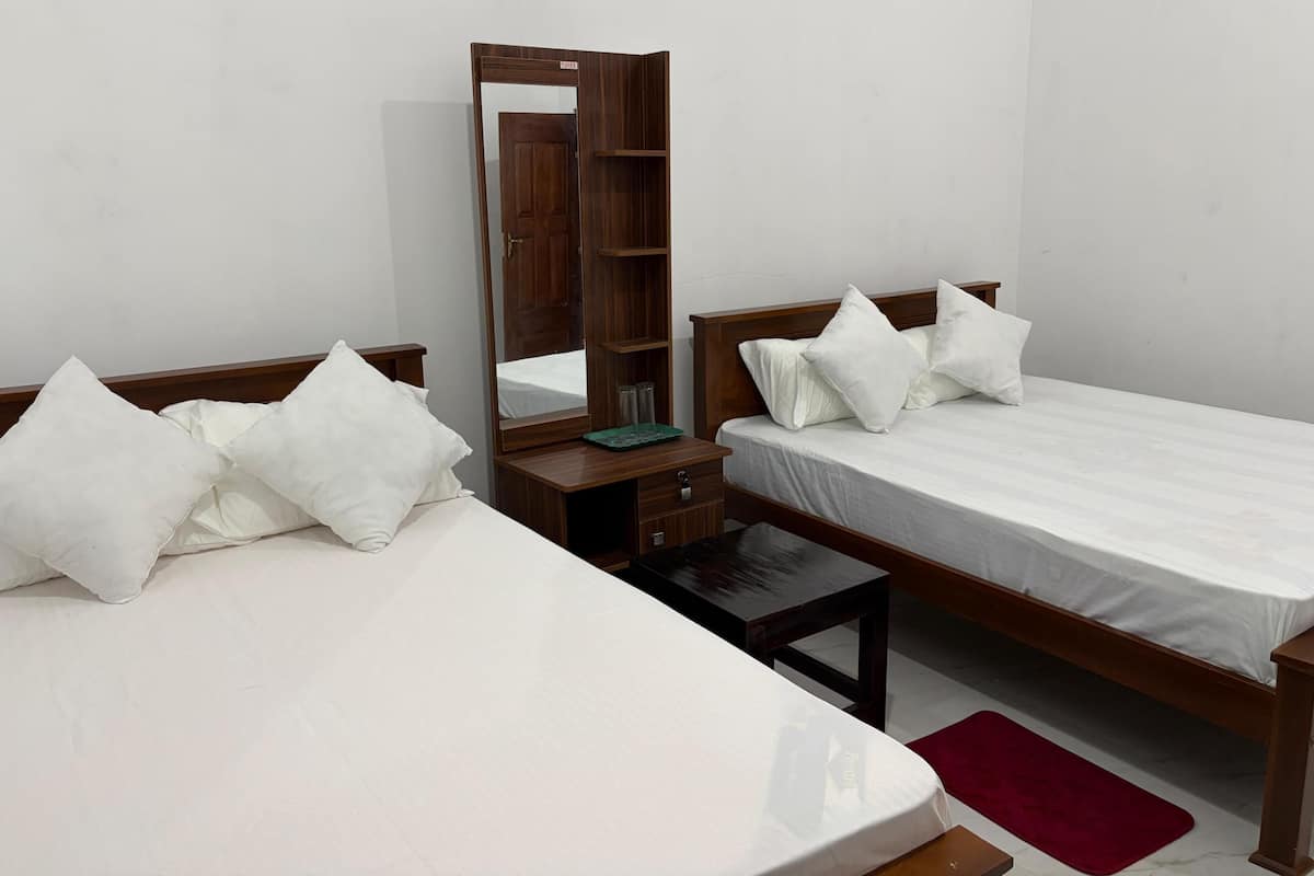 Quarto com duas camas, cómoda de madeira, espelho e tapete vermelho.