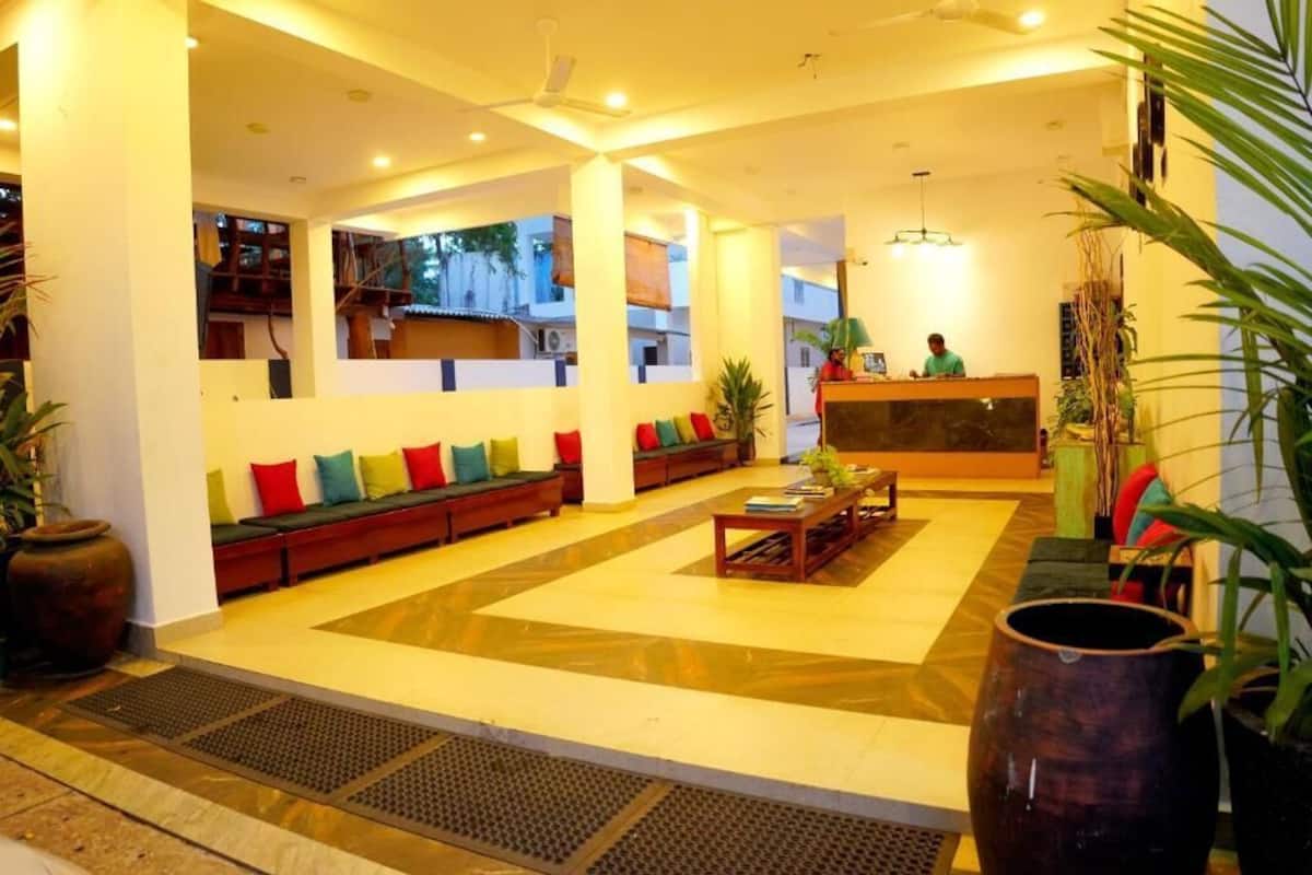 Um saguão de hotel com balcão de recepção, área de estar e vista para o exterior.