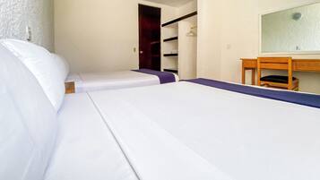 Quarto de hotel com cama, escrivaninha de madeira e guarda-roupa.