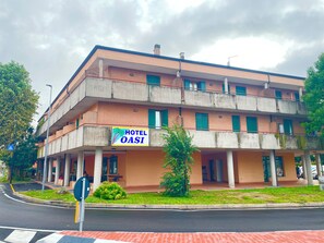 Edifício de vários andares com uma placa indicando 'HOTEL OASI' e uma entrada visível.