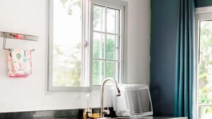 Uma cozinha moderna com armários escuros, uma janela e vista para o verde lá fora.