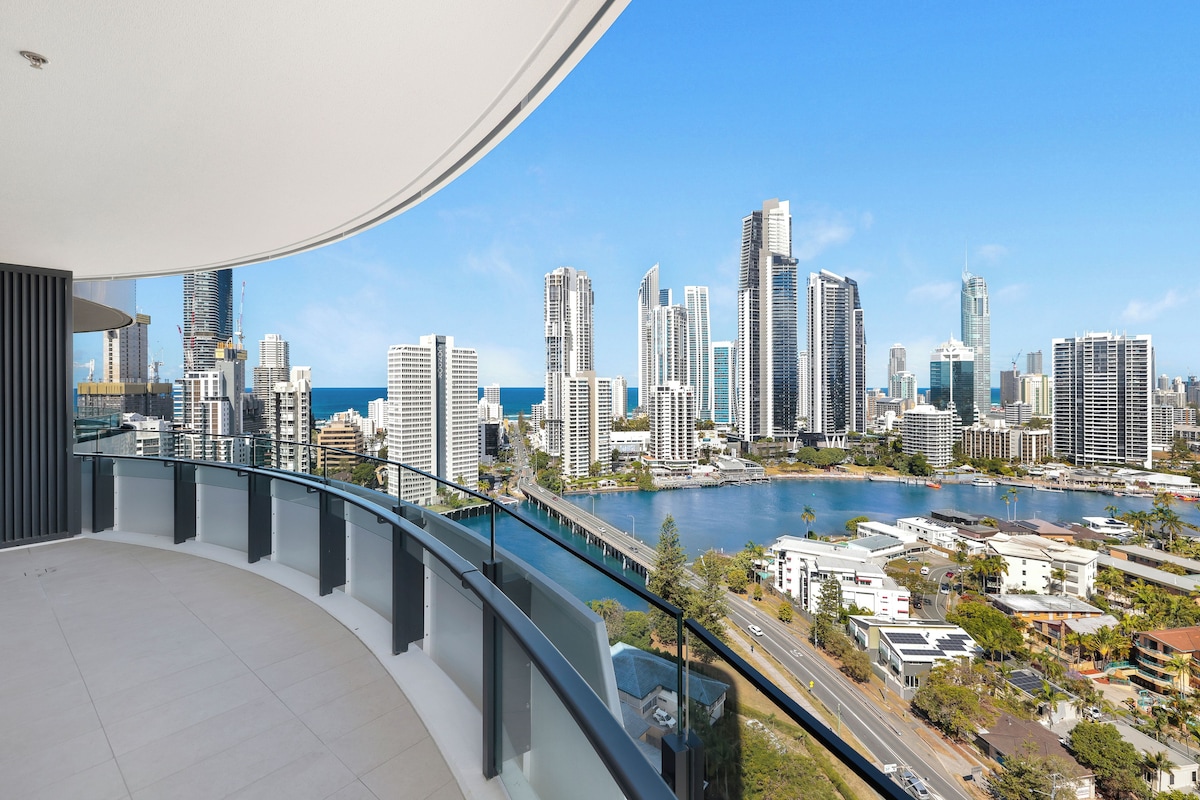 Um edifício alto com vista para o horizonte da cidade e um corpo de água.