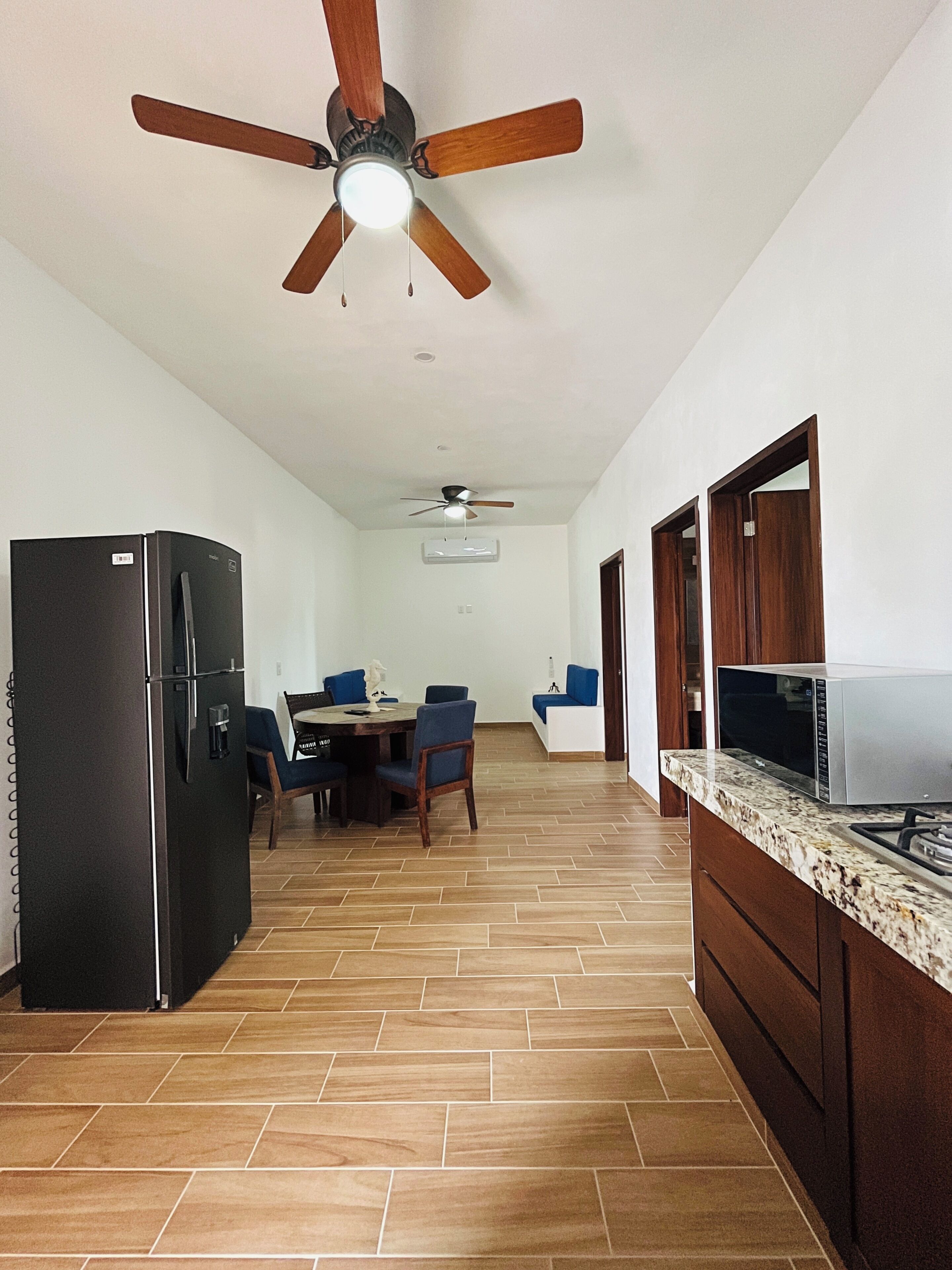 Cozinha equipada com frigorífico, micro-ondas e fogão. Dispõe de zona de refeições com cadeiras e mesa.