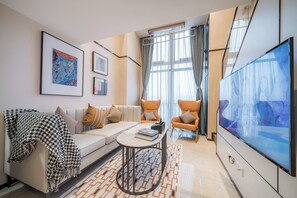 Uma sala de estar moderna com sofá, poltronas, mesa de centro, televisão de tela plana e obras de arte nas paredes.
