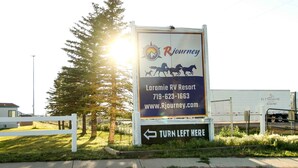 Placa do Laramie RV Resort com informações de contato e um site.