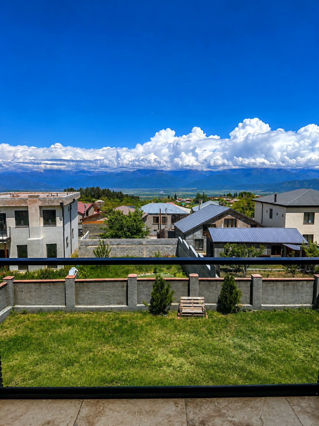 Bairro residencial com casas modernas, gramado e vista clara para montanhas ao longe.