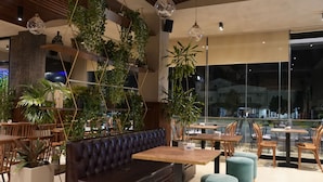 Um interior moderno com sofá de couro, mesas de madeira e plantas penduradas.