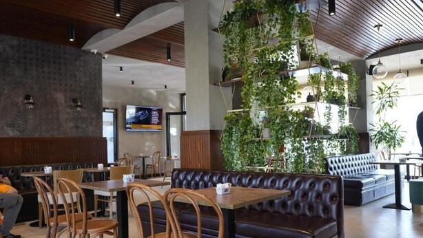 Interior de restaurante moderno com assentos de couro, mesas de madeira e parede com jardim vertical.
