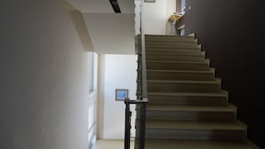 Uma escadaria com corrimão, um quadro na parede e uma janela à esquerda.