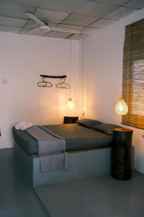 Uma cama com cabeceira, uma luminária de cabeceira e um banquinho de madeira.