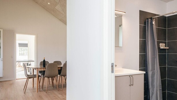 Um interior moderno com área de jantar, chuveiro com cortina e parede branca.