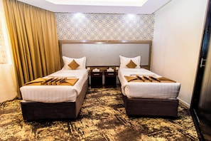 Quarto de hotel com duas camas, parede estampada e chão coberto de carpete.