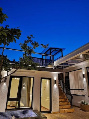 Uma casa moderna com varanda de vidro, escada de madeira e área de piscina.