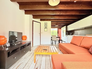 Sala de estar com sofá, televisão e mesa de centro de madeira.
