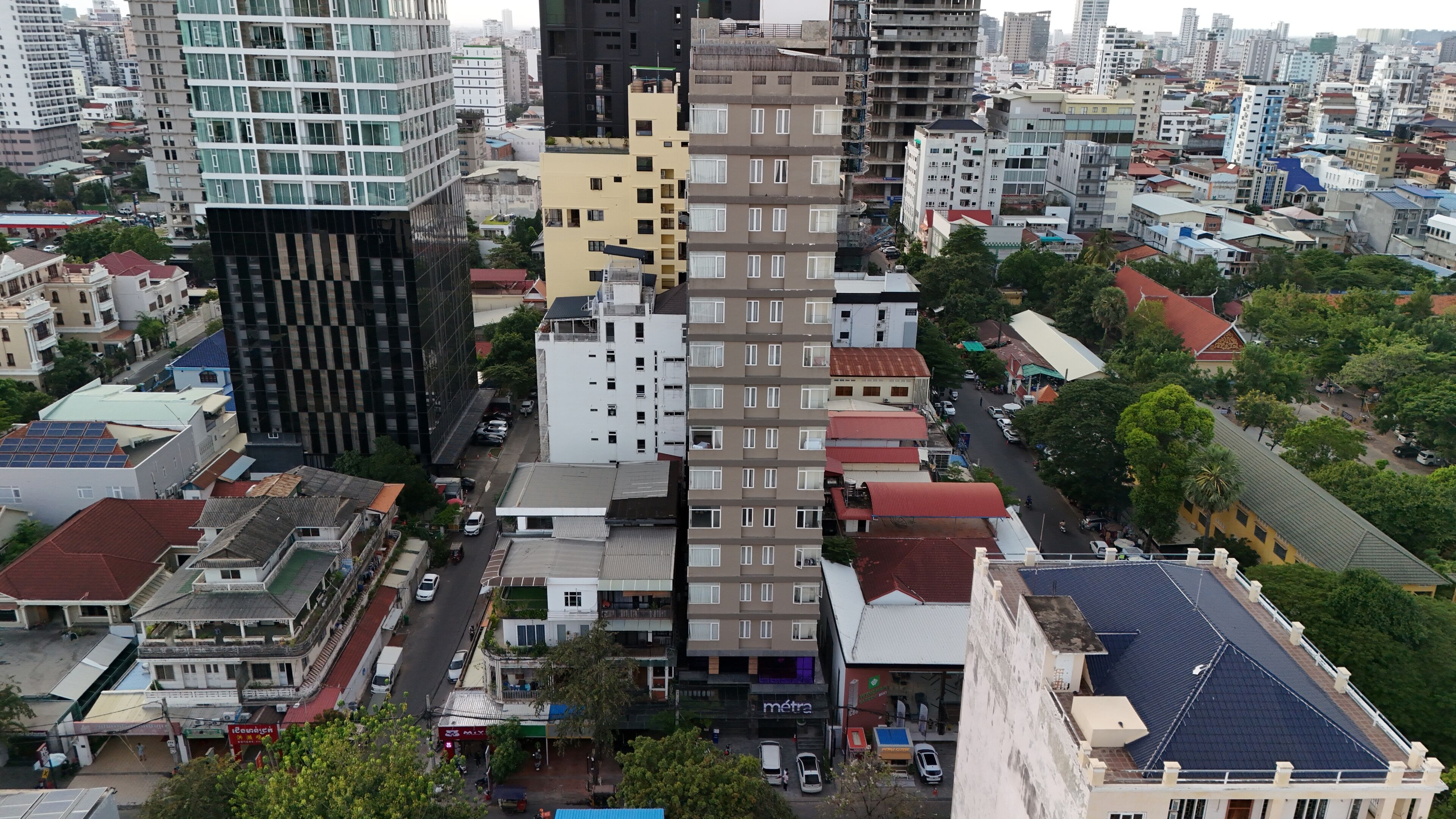Um edifício alto com vários andares, cercado por outros edifícios e ruas.