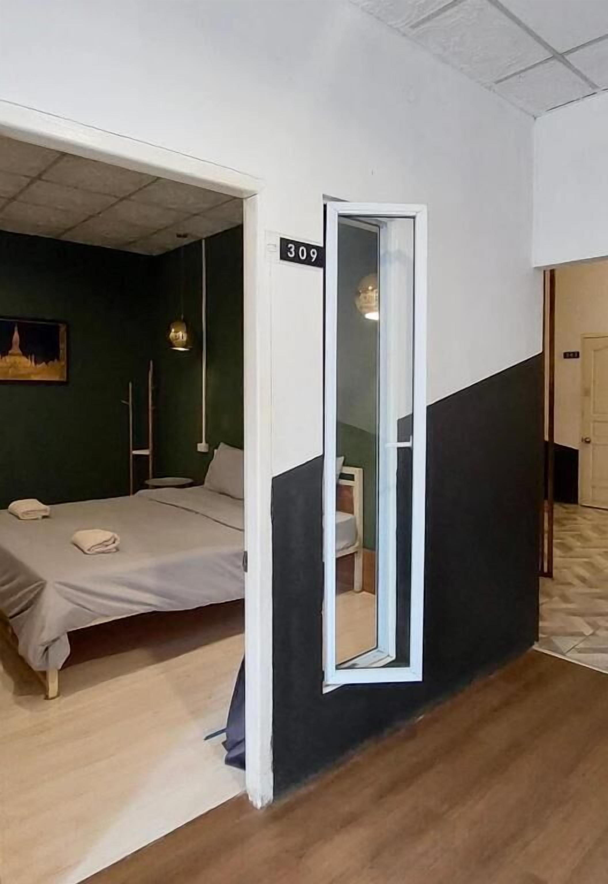 Quarto de hotel com uma cama, um espelho e uma porta com o número 309.