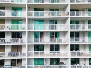 Um edifício de vários andares com varandas, cada uma com guarda-corpo branco e vista para a rua.