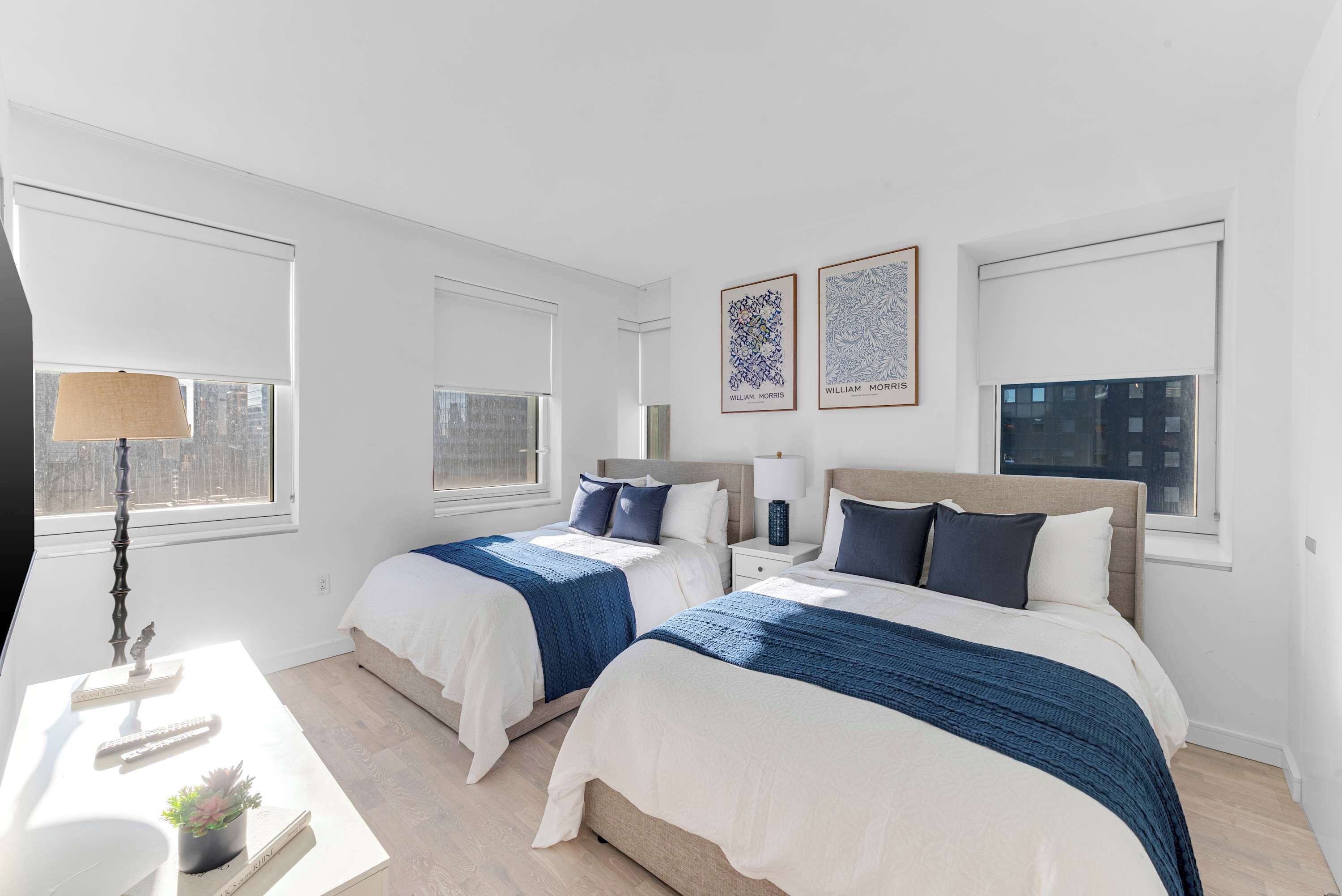 Quarto de hotel moderno com duas camas, uma escrivaninha e uma janela.