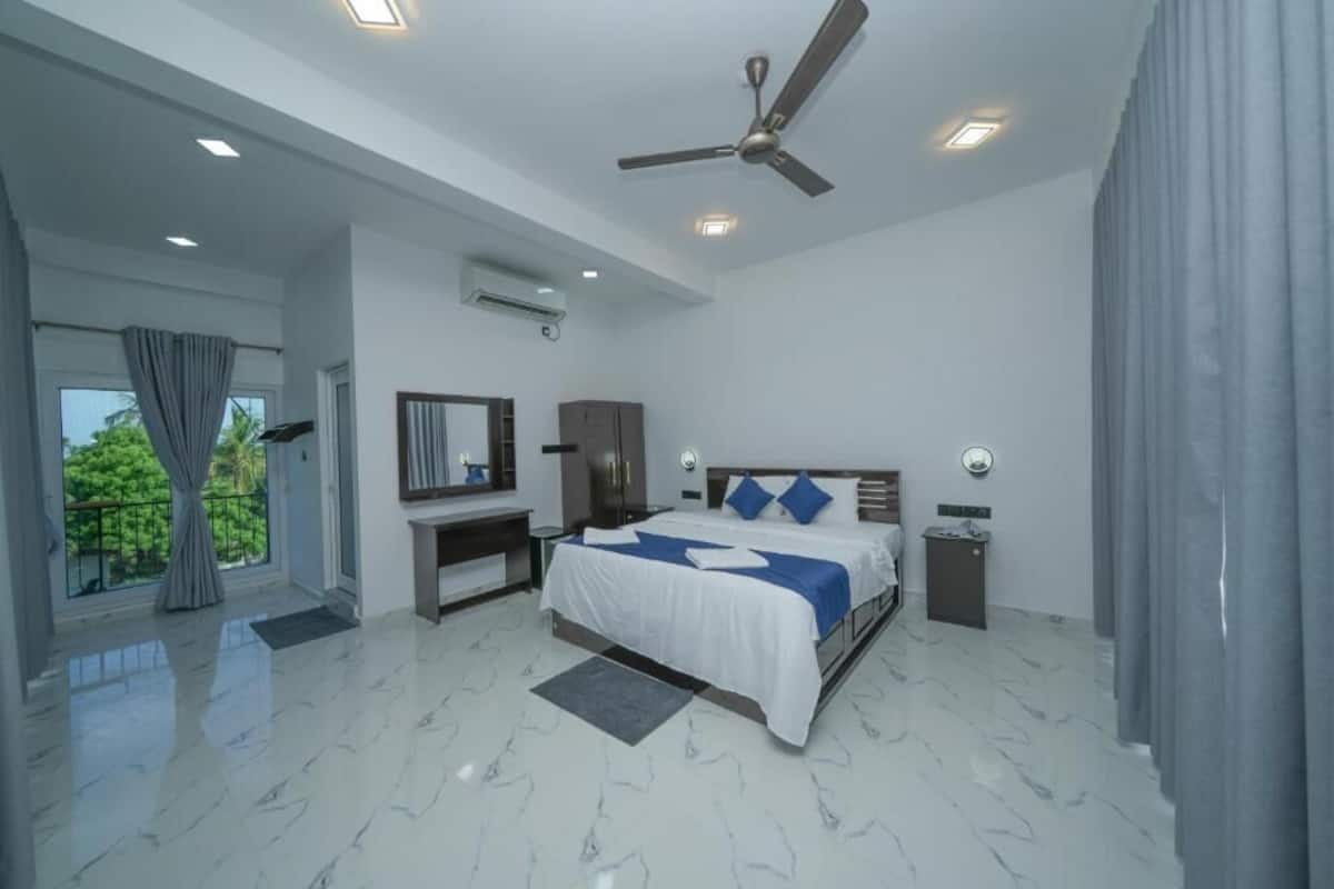 Quarto moderno com cama, ventilador de teto e varanda com cortinas.
