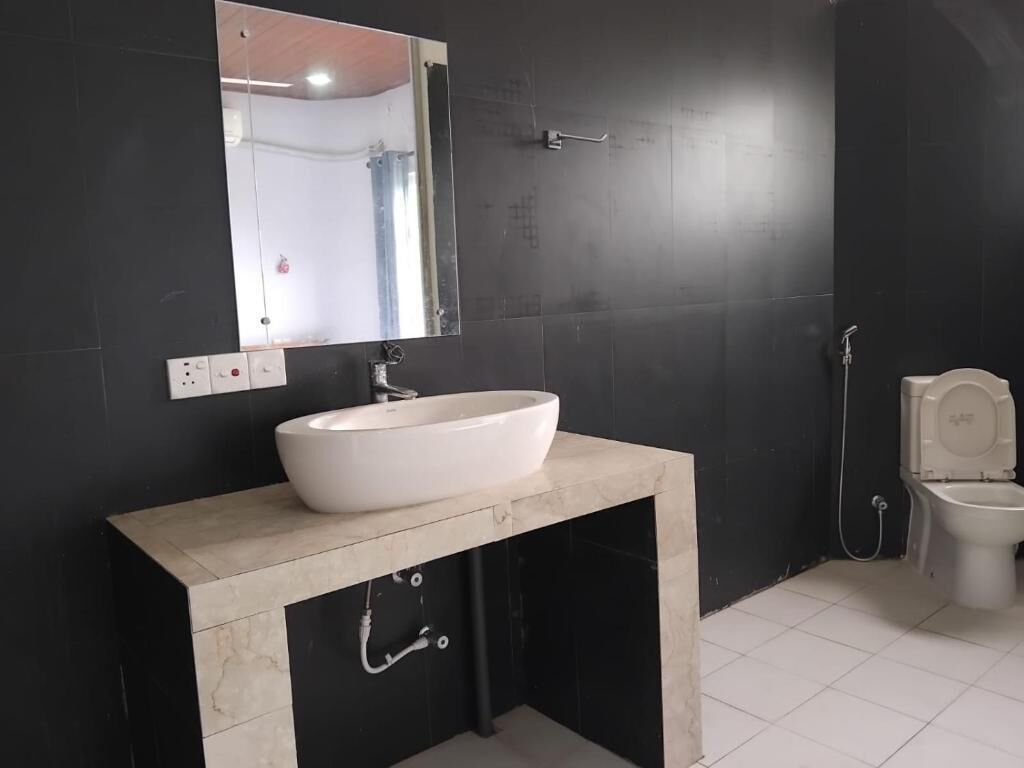 Uma casa de banho com uma sanita, um lavatório e um espelho.
