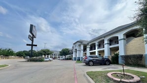 Um hotel de vários andares com um pátio central, estacionamento e céu aberto.