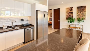 Cozinha moderna com eletrodomésticos de aço inoxidável, bancada de mármore e área de refeições com mesa e cadeiras de mármore.