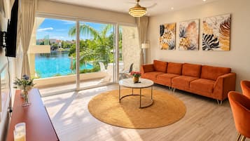 Uma sala de estar moderna com um sofá, uma mesa de centro redonda e vista para uma piscina.