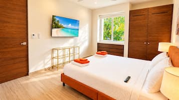 Quarto de hotel com cama, televisão, janela e vista para áreas verdes, além de um guarda-roupa.