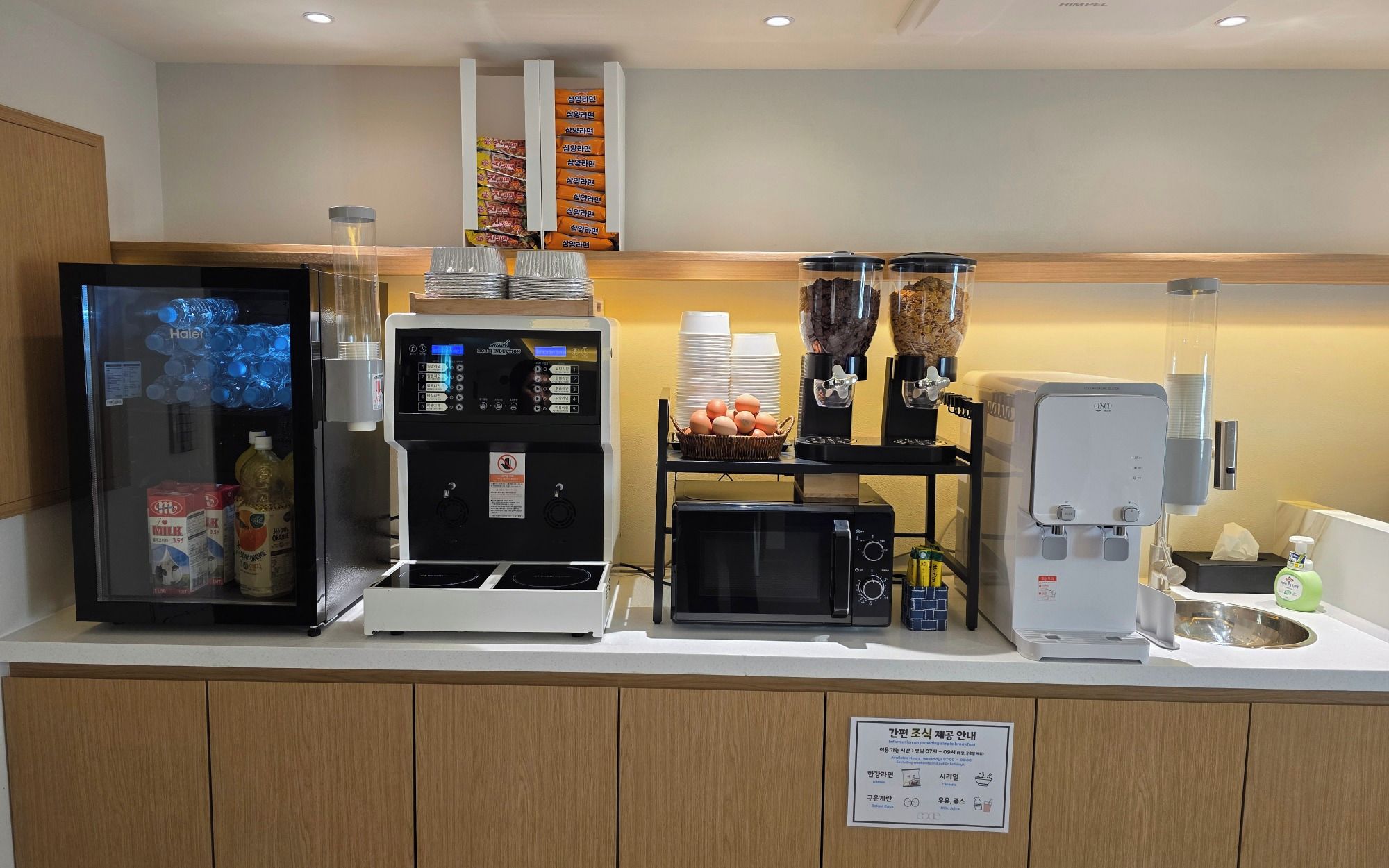 Balcão de café da manhã com geladeira, cafeteira, micro-ondas e bebedouro.