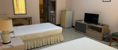 Quarto de hotel com duas camas, uma escrivaninha com luminária, televisão, guarda-roupa e um quadro na parede.