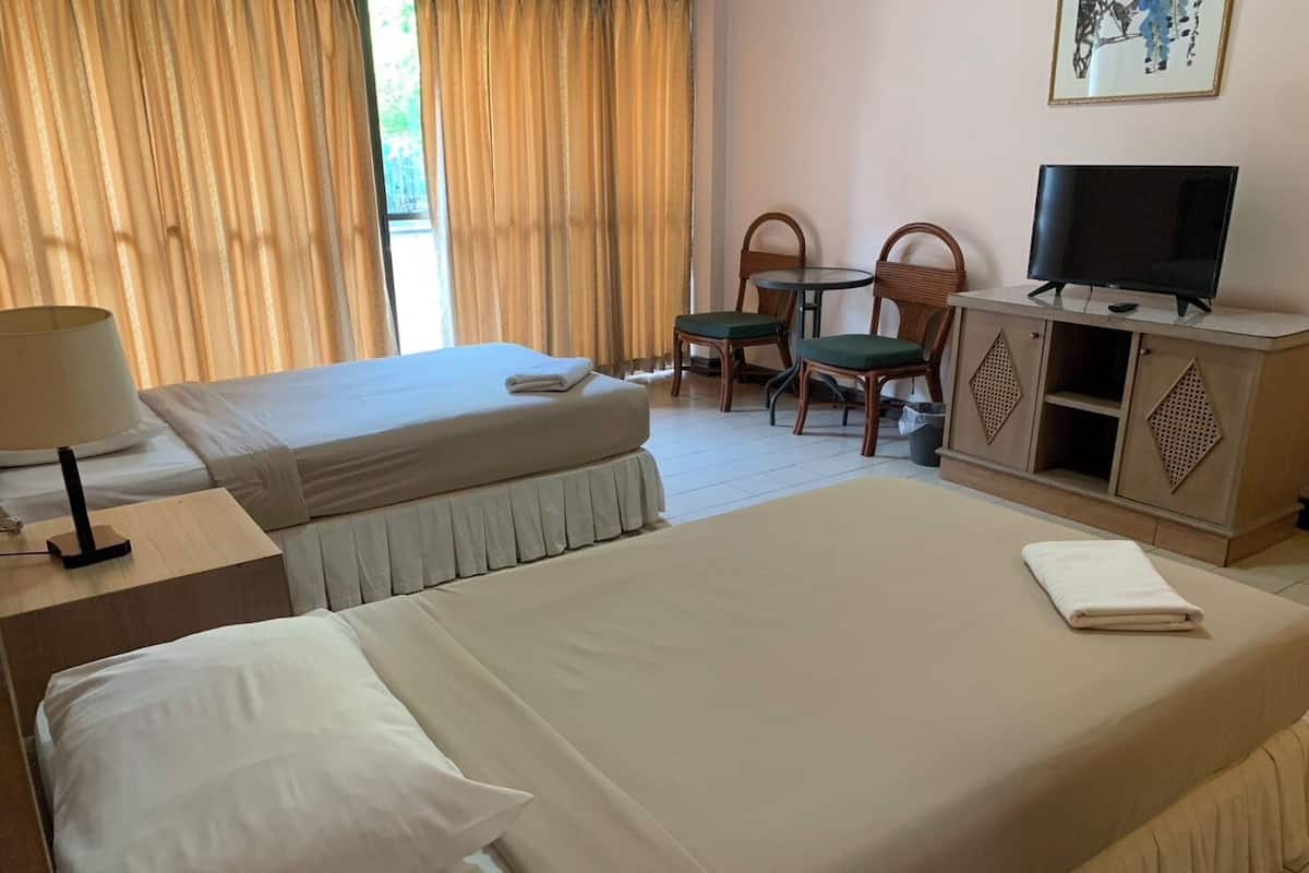 Quarto de hotel com duas camas, televisão, escrivaninha e uma cadeira.