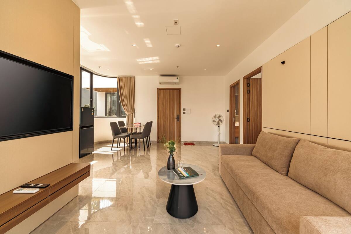 Uma sala de estar moderna com televisão de tela plana, um sofá, uma mesa de centro e um espaço de jantar com cadeiras e uma mesa.