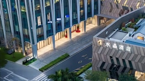 Um hotel moderno com fachada geométrica marcante, área externa bem cuidada e sinalização clara.