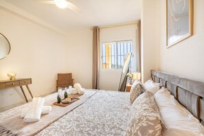 Quarto de hotel com uma cama, mesa de cabeceira, espelho e janela.