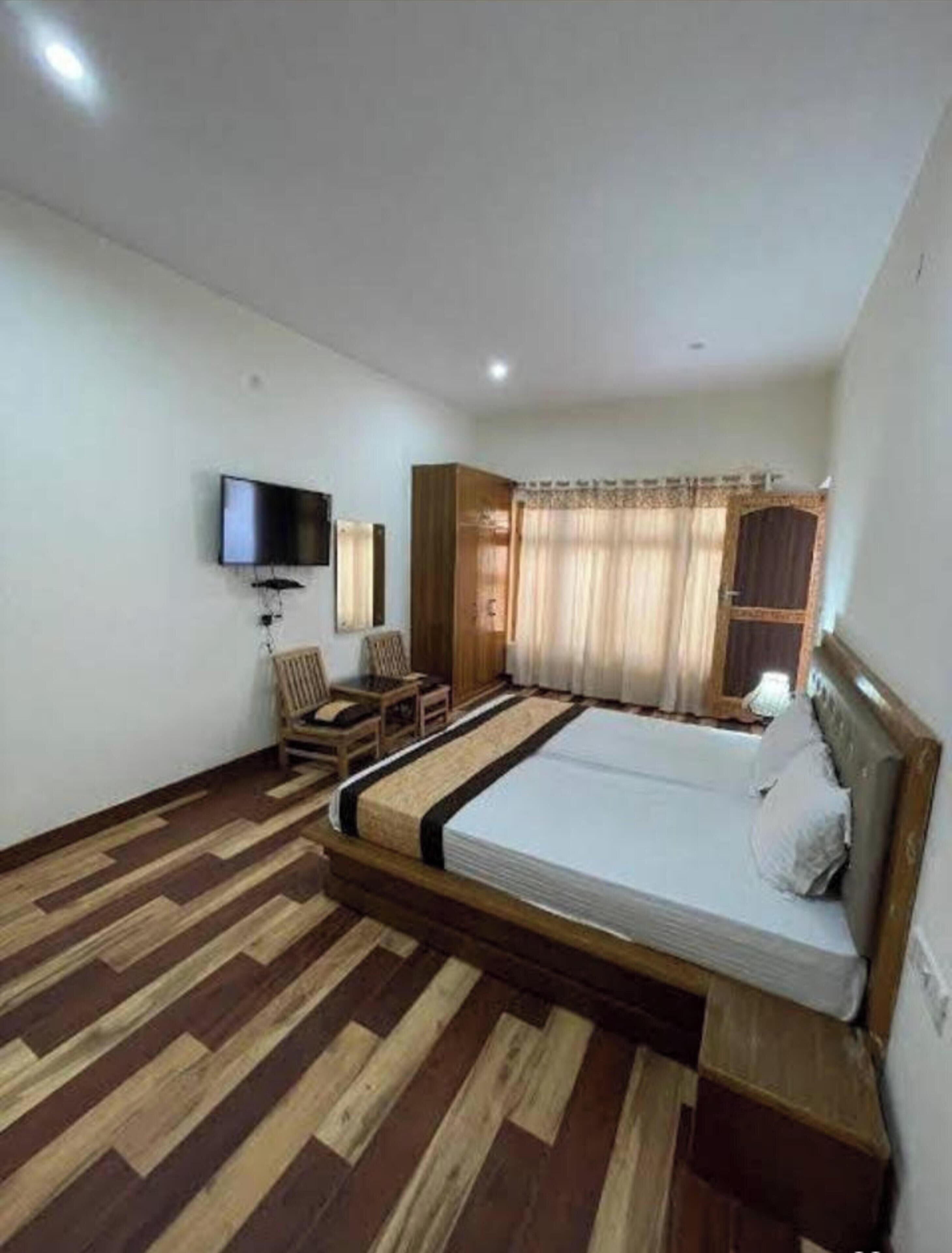 Um quarto com cama, televisão, guarda-roupa e uma cadeira.