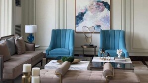 Uma sala de estar moderna com um sofá, duas poltronas, uma mesa de centro e um grande quadro abstrato na parede.