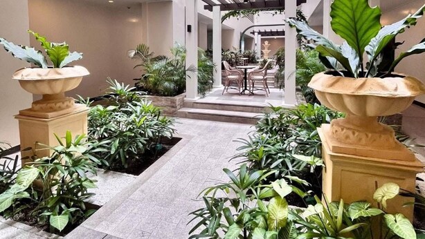 Um saguão de hotel com área de estar central, plantas em vasos e design arquitetônico moderno.