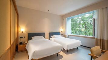 Quarto de hotel com duas camas, uma escrivaninha e uma cadeira.