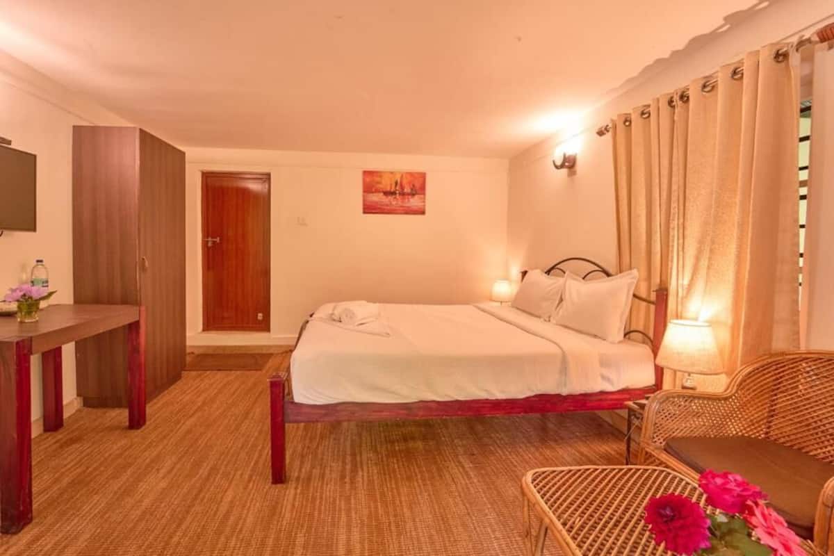 Quarto de hotel com cama, mesa de cabeceira, cadeira e um quadro na parede.