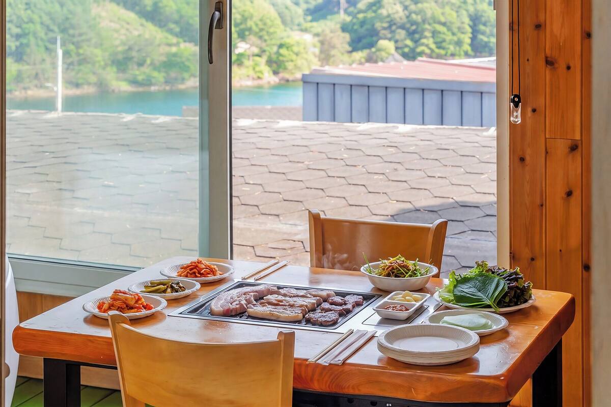 Uma mesa de jantar com comida, vista para um lago e decoração em madeira.