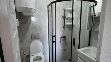 Casa de banho com sanita, chuveiro e lavatório.