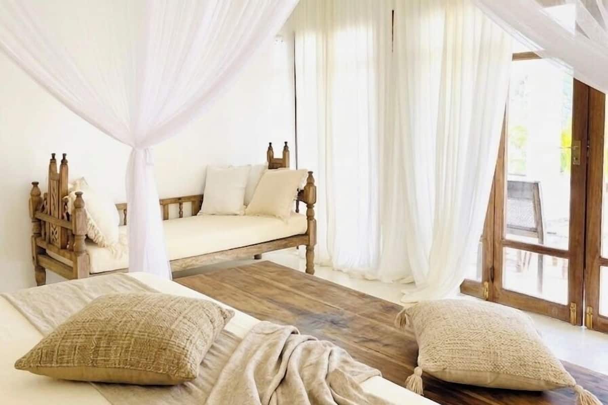 Um quarto com uma cama, um banco de madeira e um sofá.