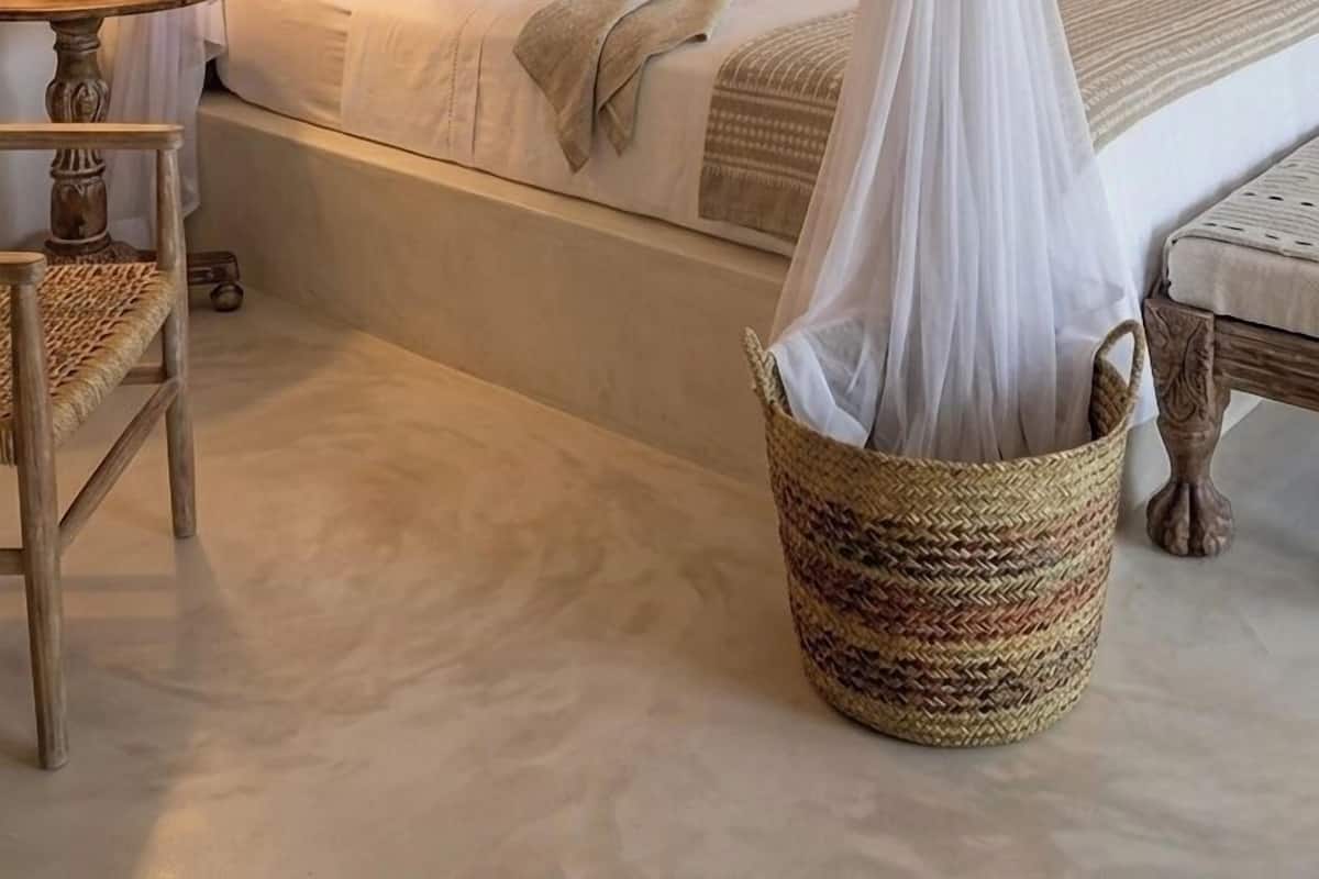 Quarto com cama de dossel, mesa de cabeceira com abajur e cesto de palha.