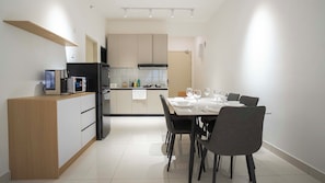 Uma cozinha moderna com área de jantar, com micro-ondas embutido, forno e mesa de jantar para seis pessoas.
