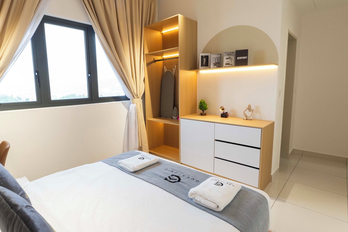 Quarto moderno com cama, mesa de cabeceira, guarda-roupa e um pequeno espaço de trabalho com livros.