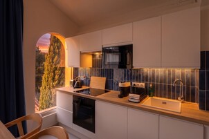 Cozinha moderna com forno embutido, pia e janela com vista para uma árvore.